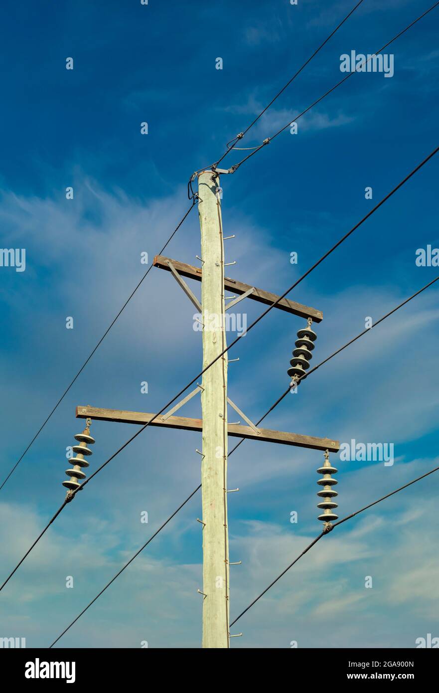 Photograph of a wooden telephone post and cables against a blue sky ...