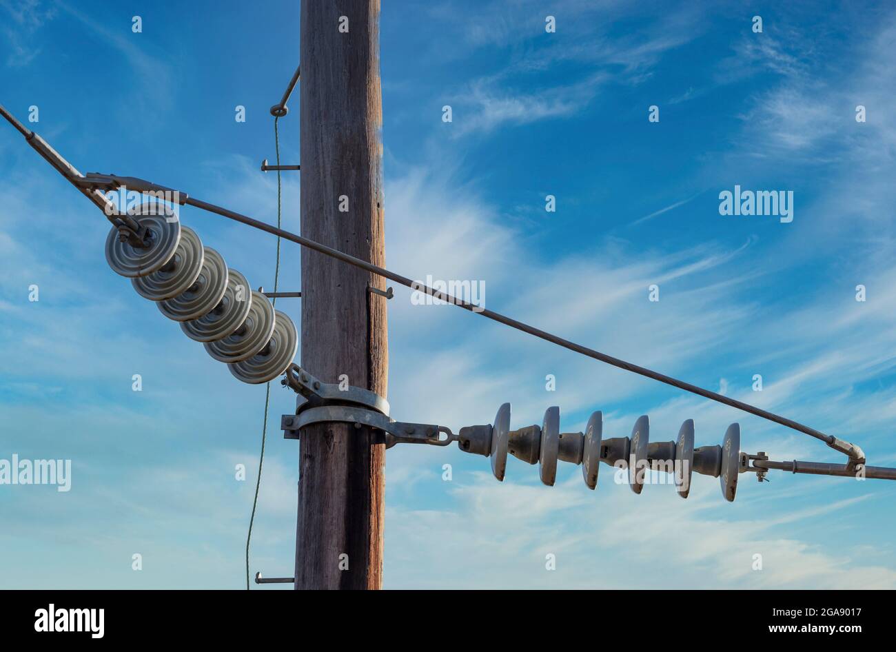 Photograph of a wooden telephone post and cables against a blue sky ...
