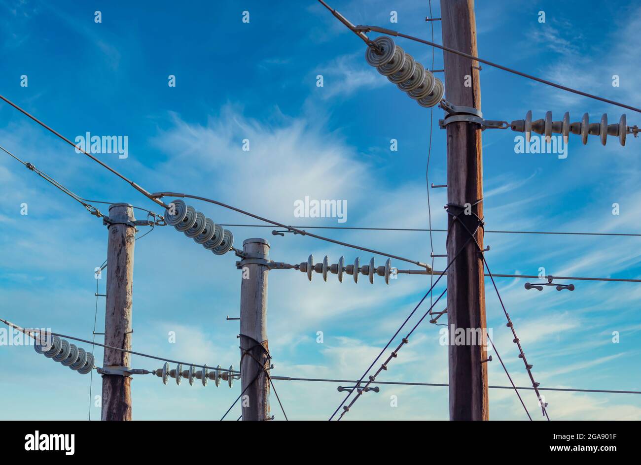 Photograph of a wooden telephone post and cables against a blue sky ...