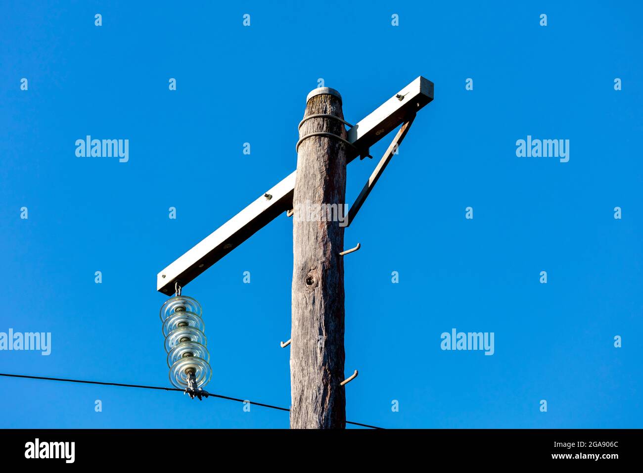 Photograph of a wooden telephone post and cables against a blue sky ...
