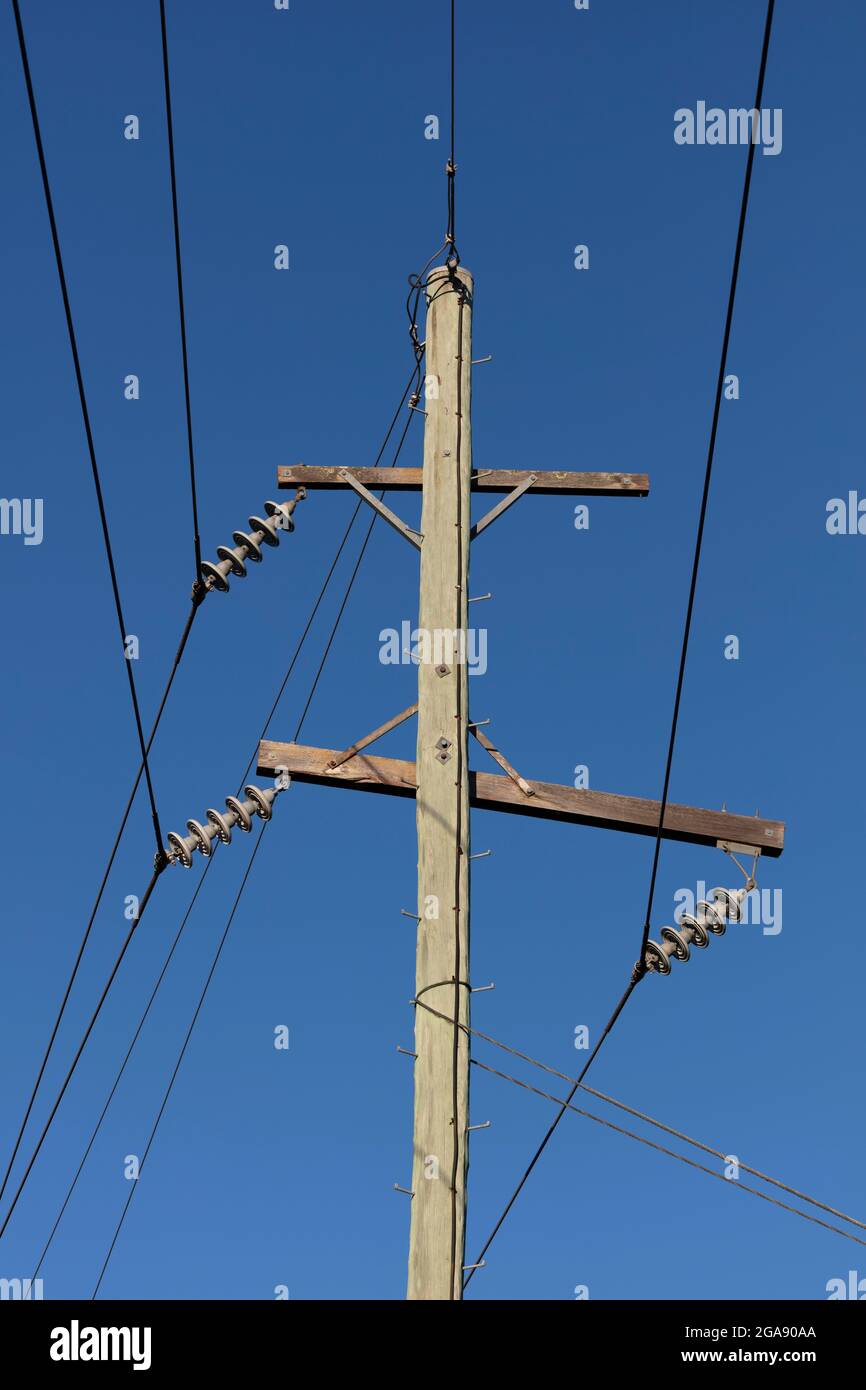 Photograph of a wooden telephone post and cables against a blue sky ...