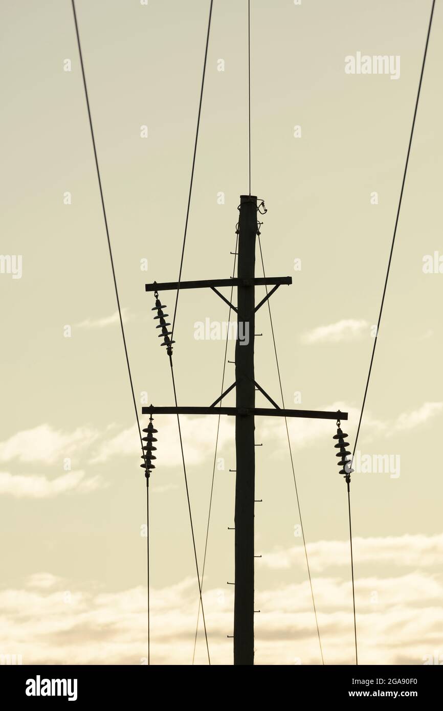 Photograph of a wooden telephone post and cables against a blue sky ...