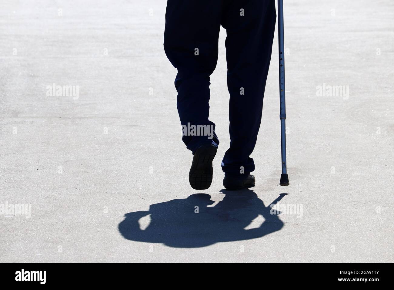 Silhouette of man walking with a cane down the street, shadow on ...