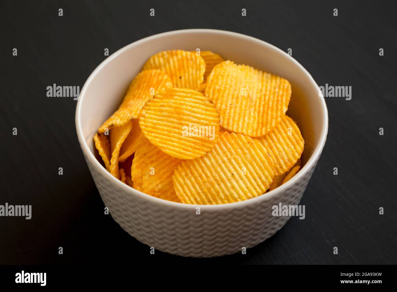 Ruffled Cheese Potato Chips in a Bowl on a black background, side view ...