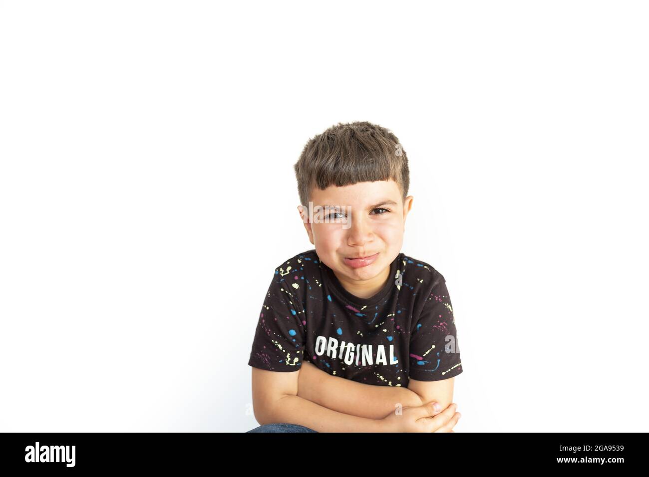 caucasian child in a disgruntled pose with arms folded on a white ...