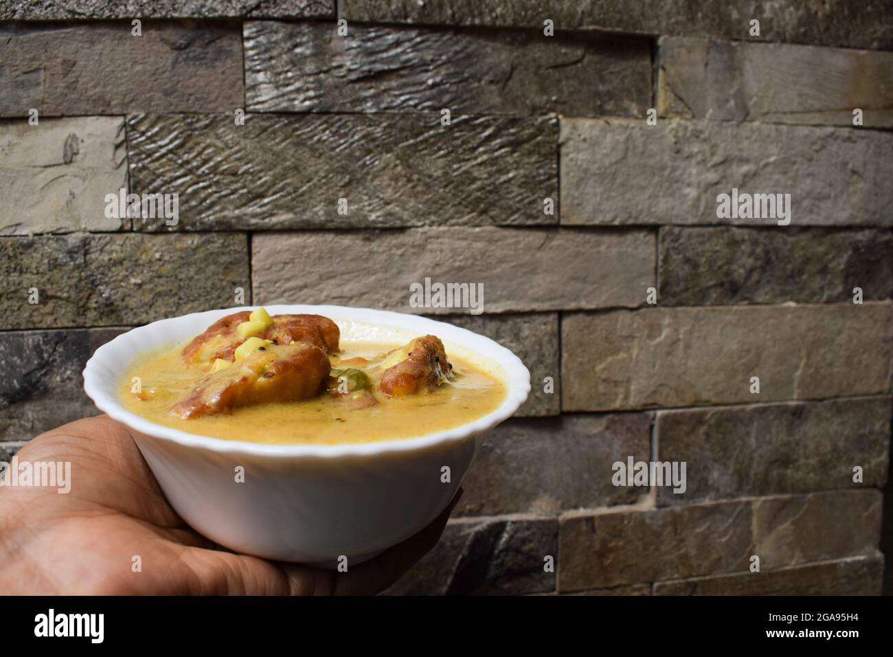 Female hand holding Kadhi pakoda or Kadhi pakora an Indian and ...