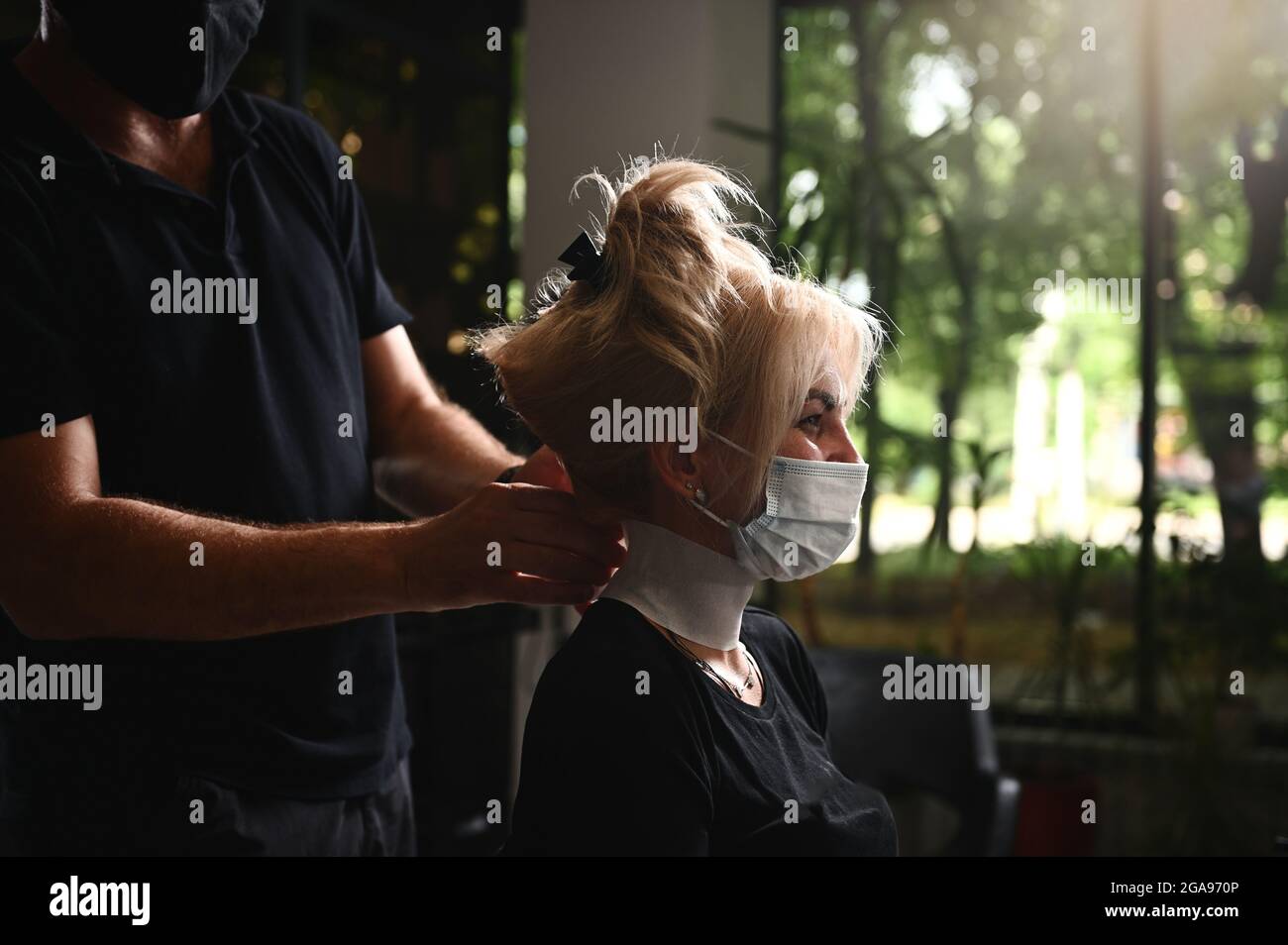 Side view of a salon client wearing a medical protective mask getting ...