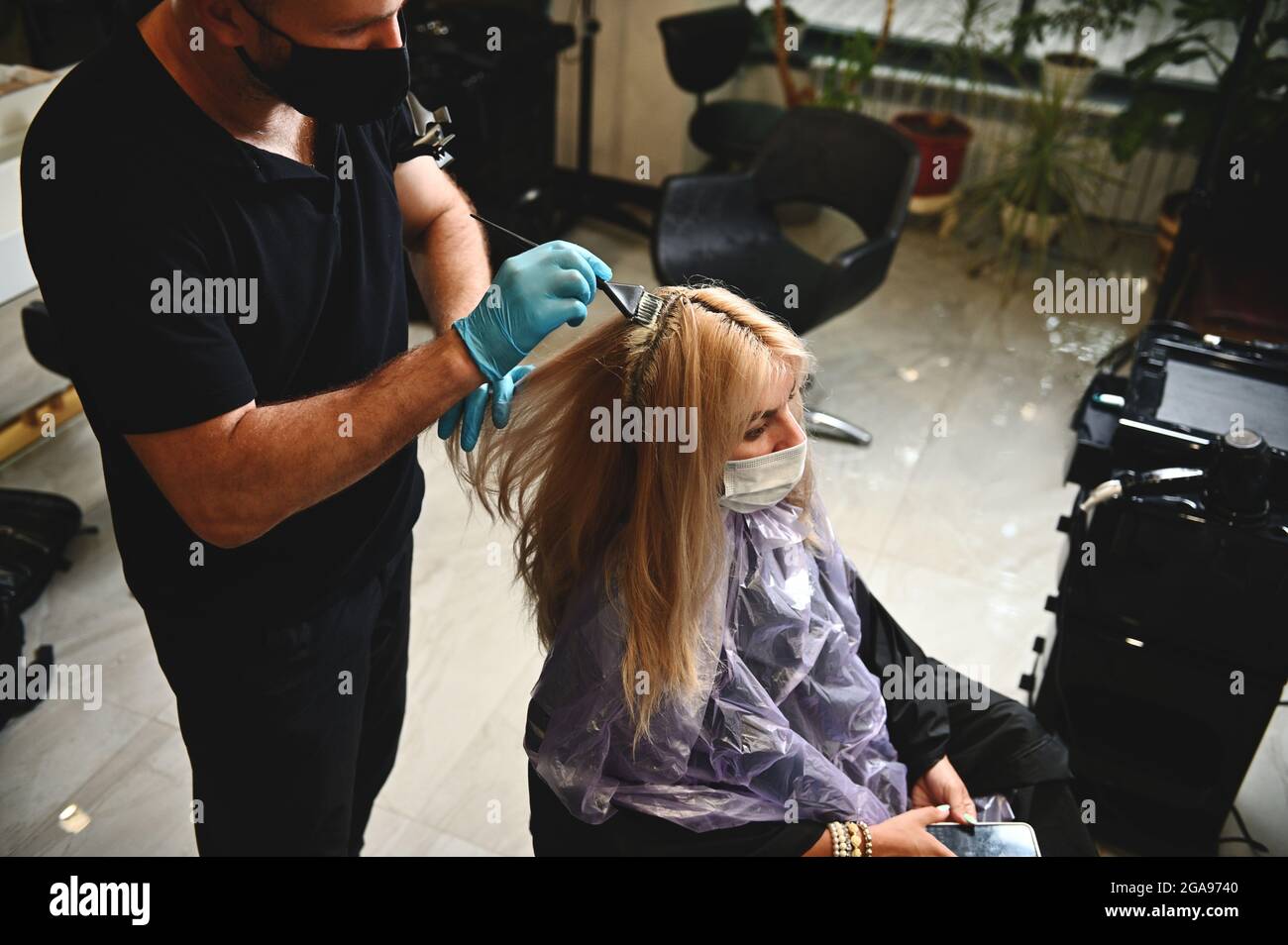 Side view of a salon client wearing a medical protective mask getting ...