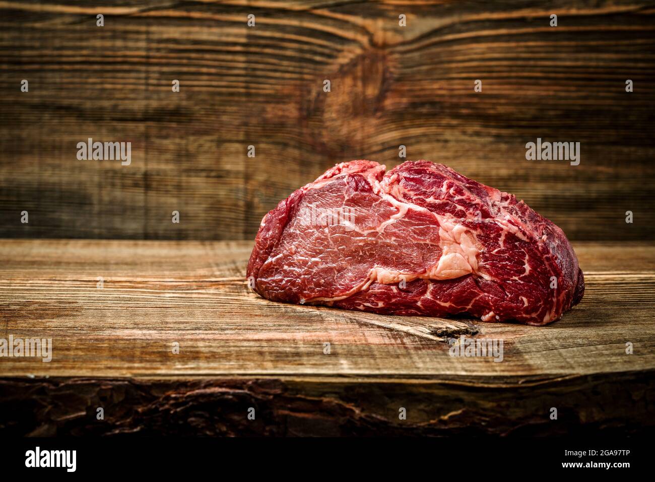Dry aged Ribeye Steak with seasoning on wooden background Stock Photo ...