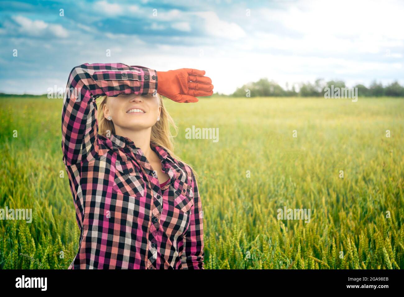 tired female agricultural worker on the background of a wheat field ...