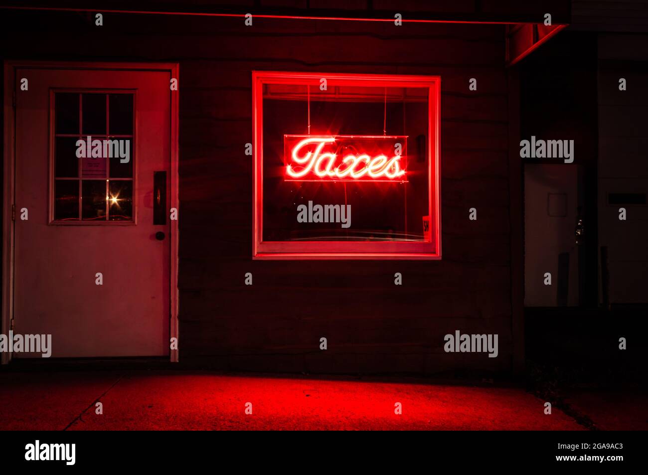 This is a photo of a neon window sign that says "Taxes Stock Photo - Alamy