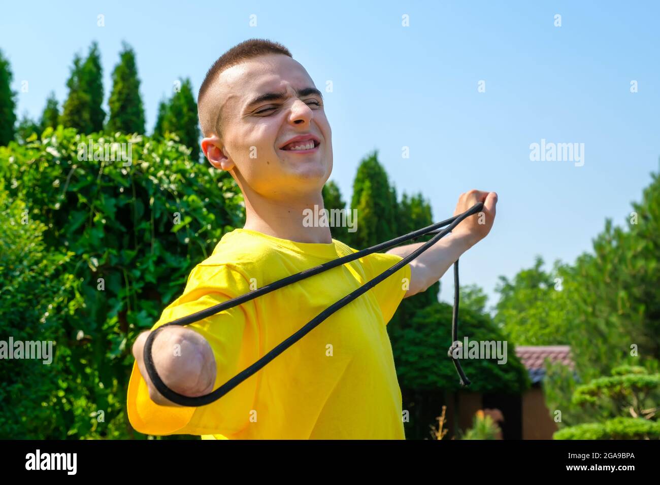 Man with amputated arm exercising with rubber elastic band outdoors ...