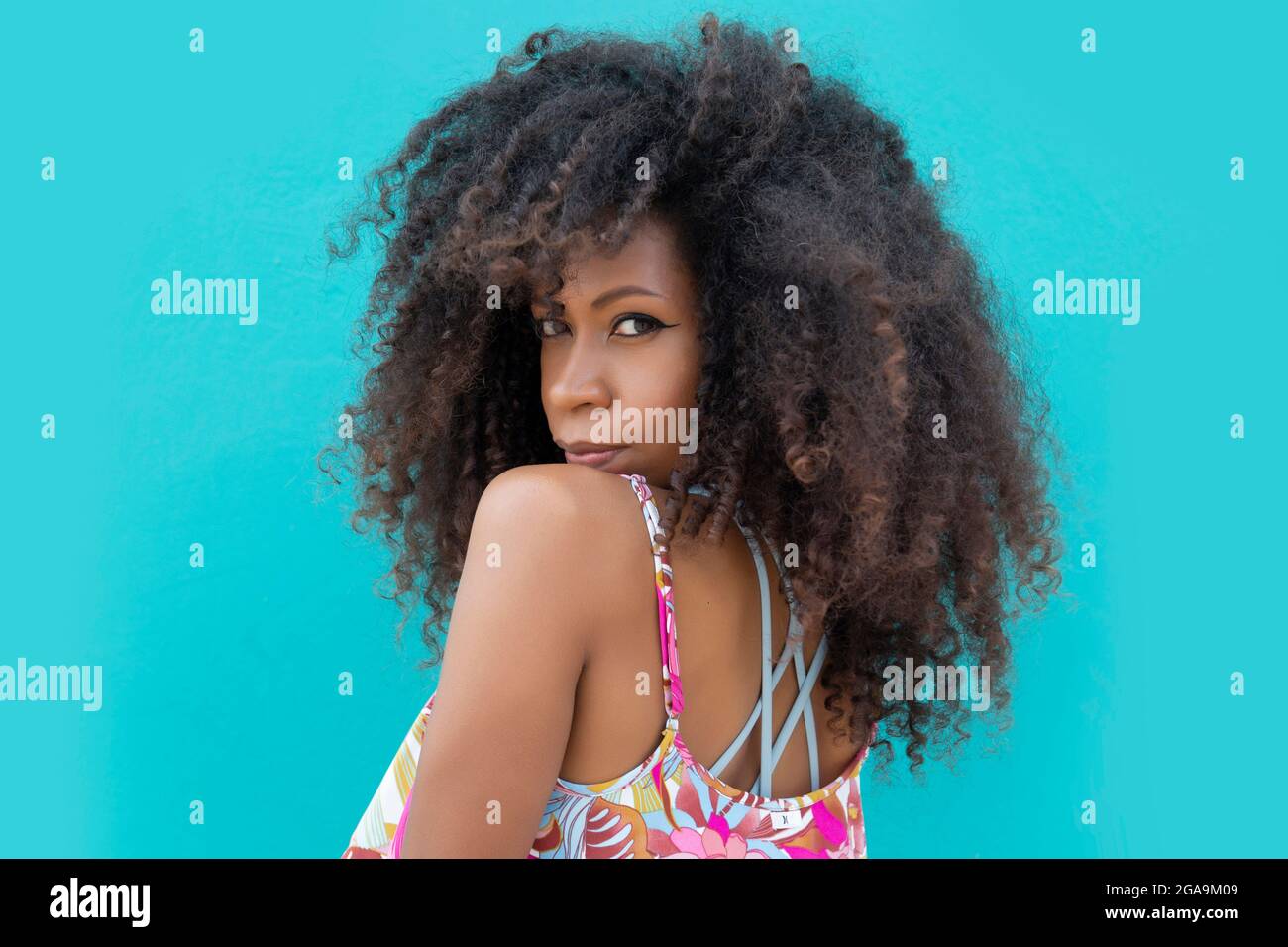 beautiful young afro woman posing flirtatiously on an aquamarine blue ...