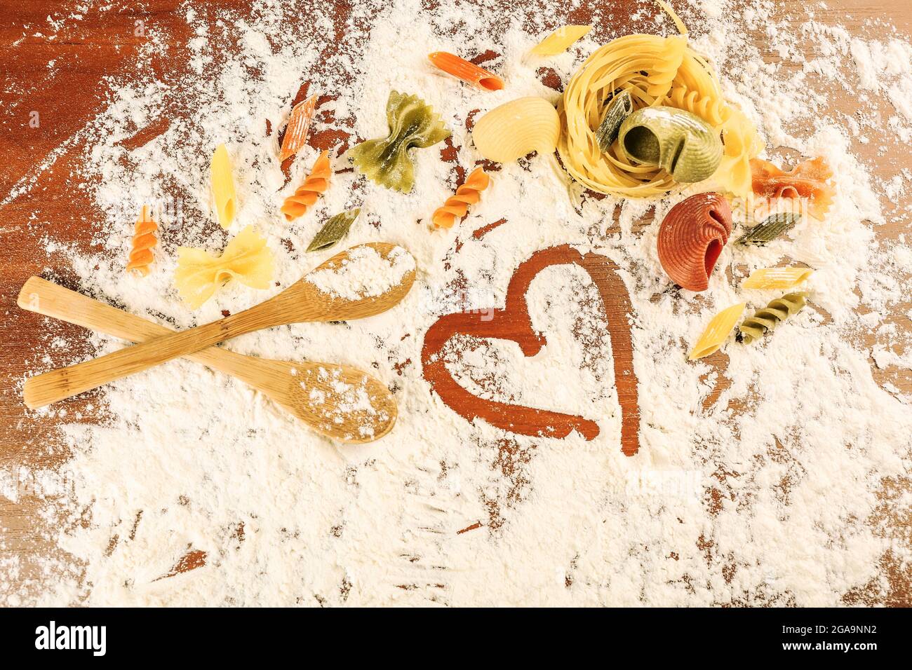 Row pasta with wooden spoons on flour background Stock Photo - Alamy