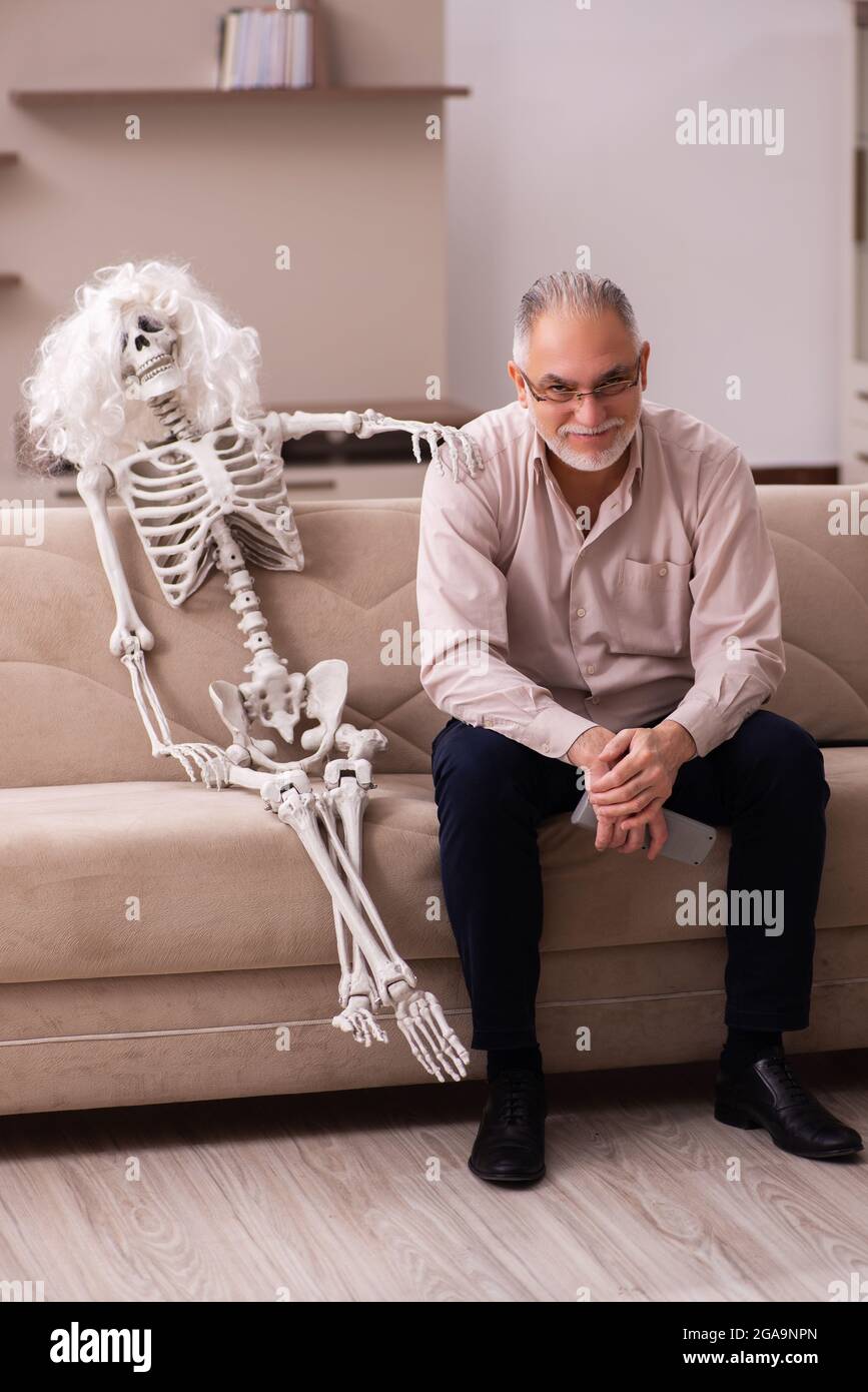 Old man sitting on the sofa with the female skeleton in undying love ...