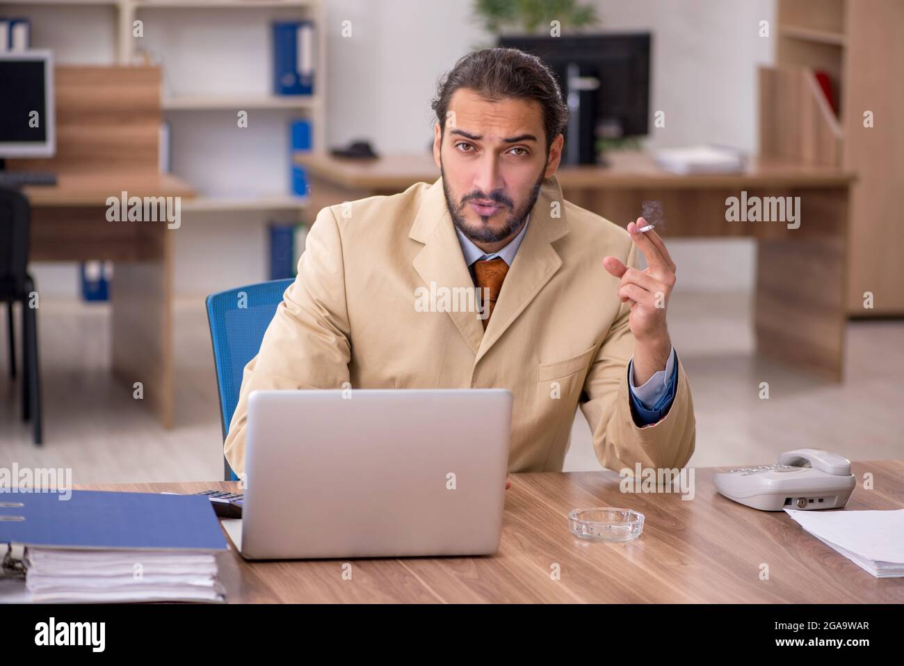 Sick cigarette addicted male employee working in the office Stock Photo ...