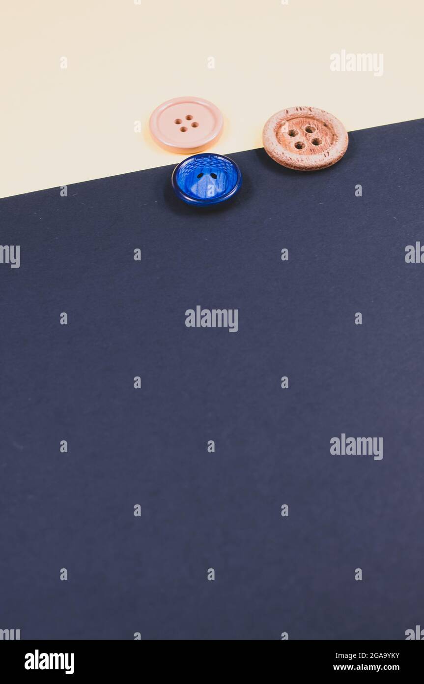 Flat lay of different sizes of sewing buttons on a beige and dark ...