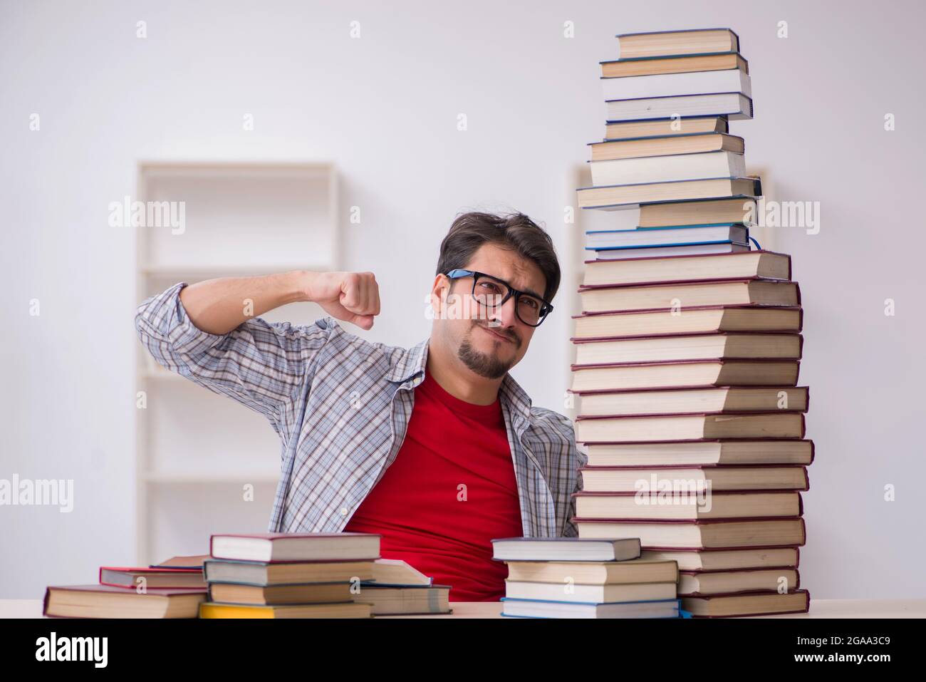 Young student and too many books in the classroom Stock Photo - Alamy