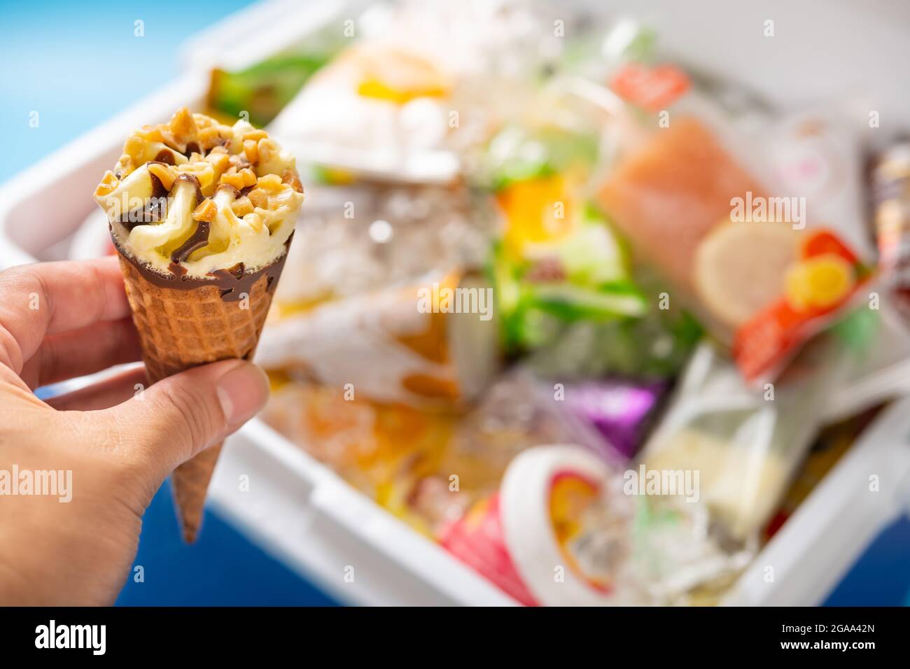 man holding an ice cream cone with box of various ice creams on ...