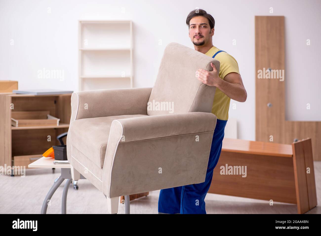 Young carpenter repairing arm-chair in the office Stock Photo - Alamy
