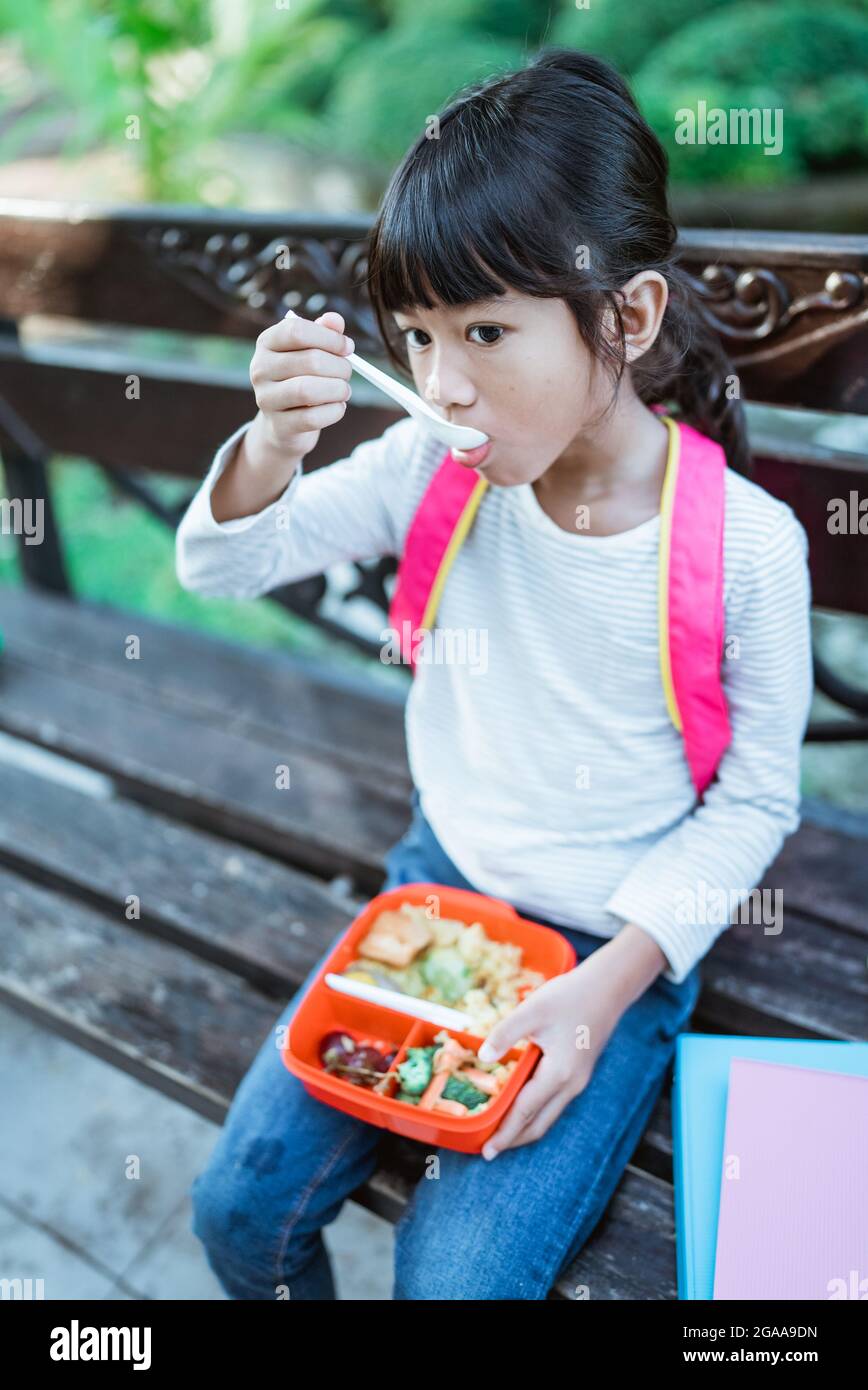 kid school student enjoying eating her meal in lunch box during school ...