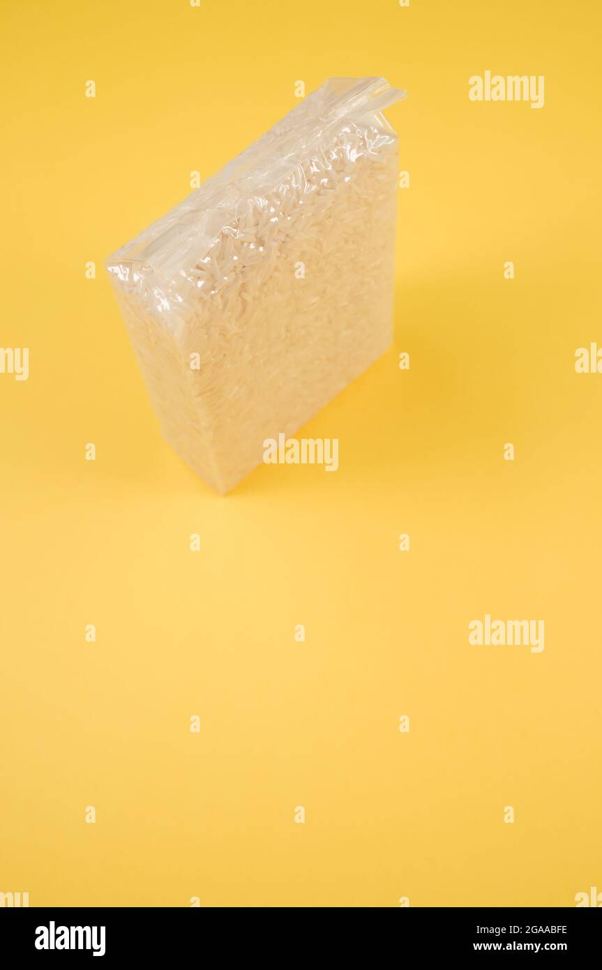 Pack of rice grains isolated on a yellow background with free space for ...