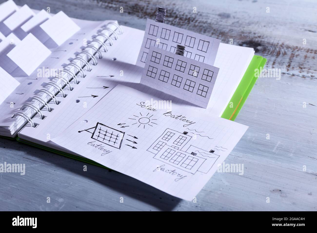 Handmade model of solar panels in notebook on wooden table, closeup ...