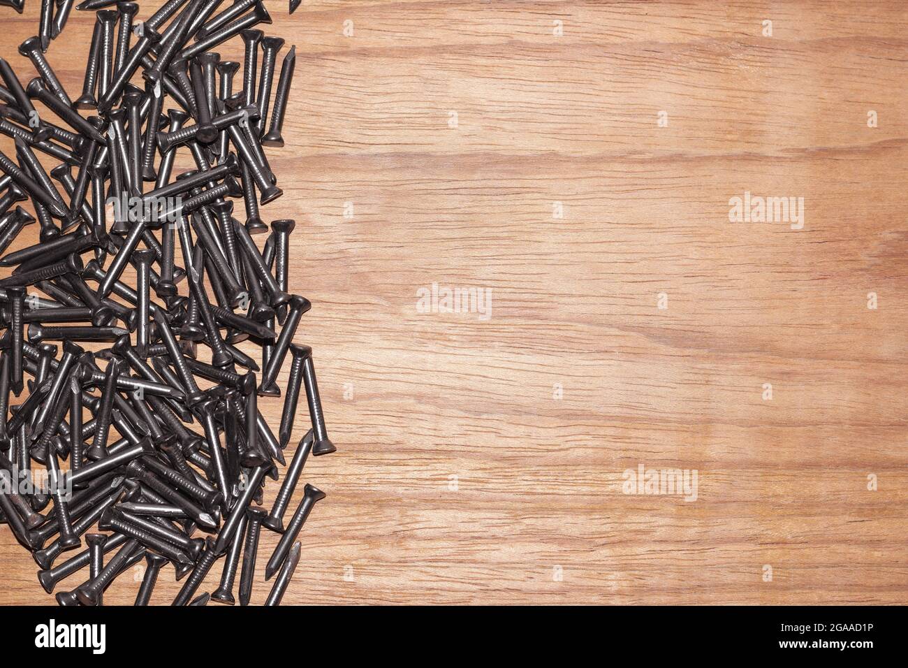 Black steel nails on wooden background, scattered to the left randomly ...