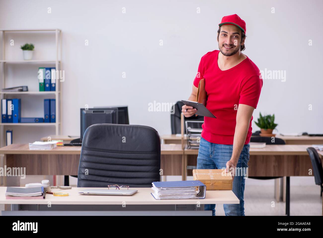 Young courier delivering post to the office Stock Photo - Alamy