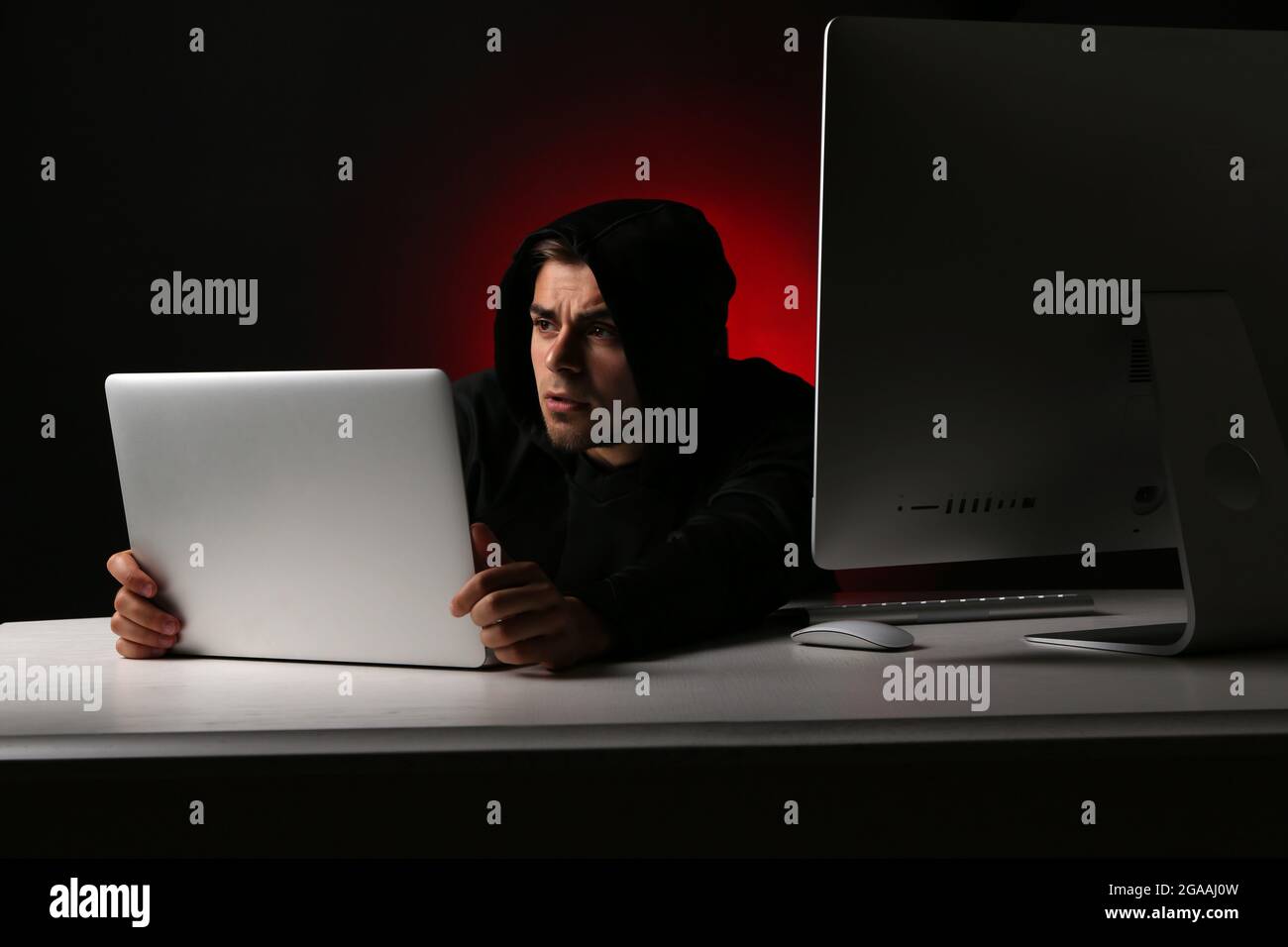 Hacker with computer and laptop on dark background Stock Photo - Alamy