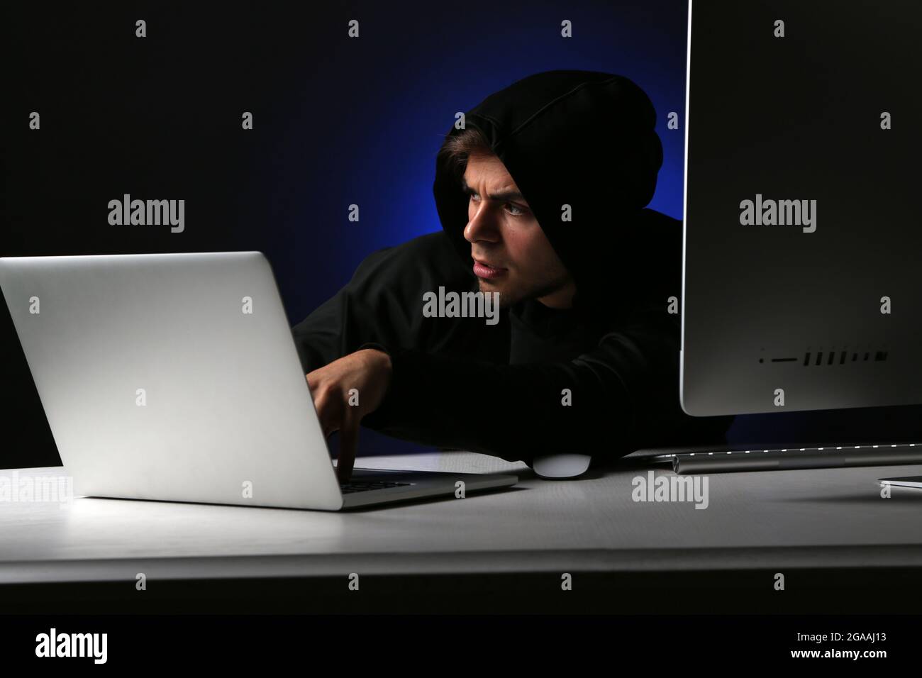 Hacker with computer and laptop on dark background Stock Photo - Alamy