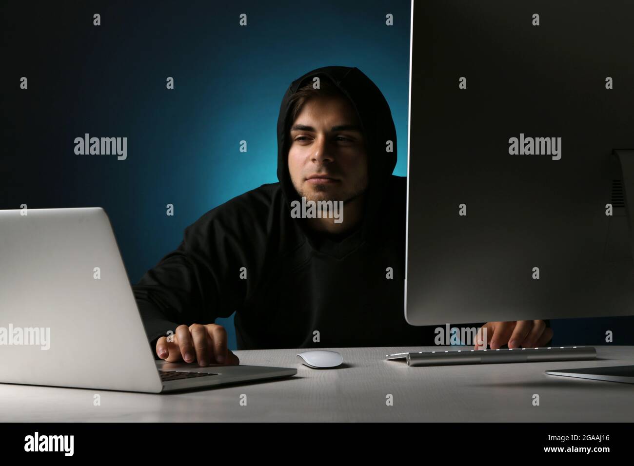 Hacker with computer and laptop on dark background Stock Photo - Alamy