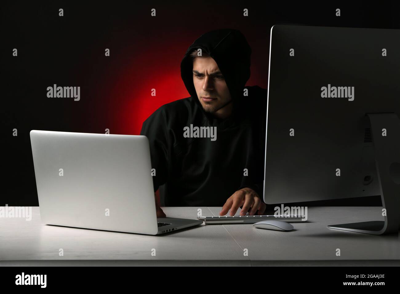 Hacker with computer and laptop on dark background Stock Photo - Alamy