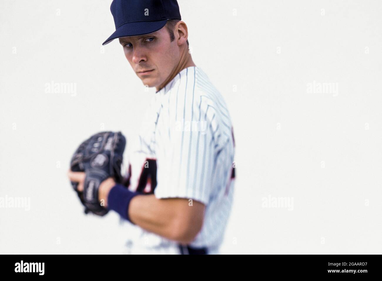 Baseball pitcher watching the runner at first base over his shoulder ...