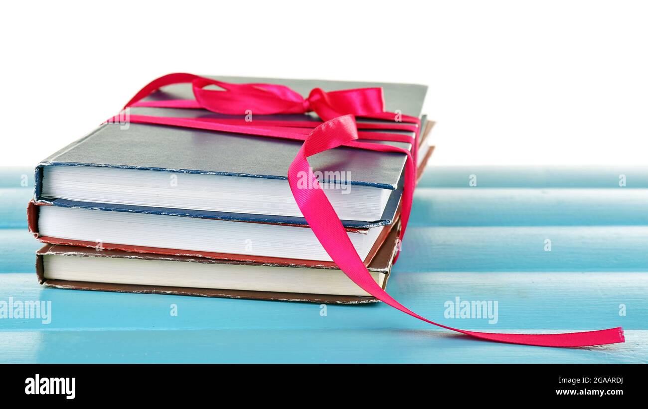 Stack of books with ribbon on table isolated on white Stock Photo - Alamy
