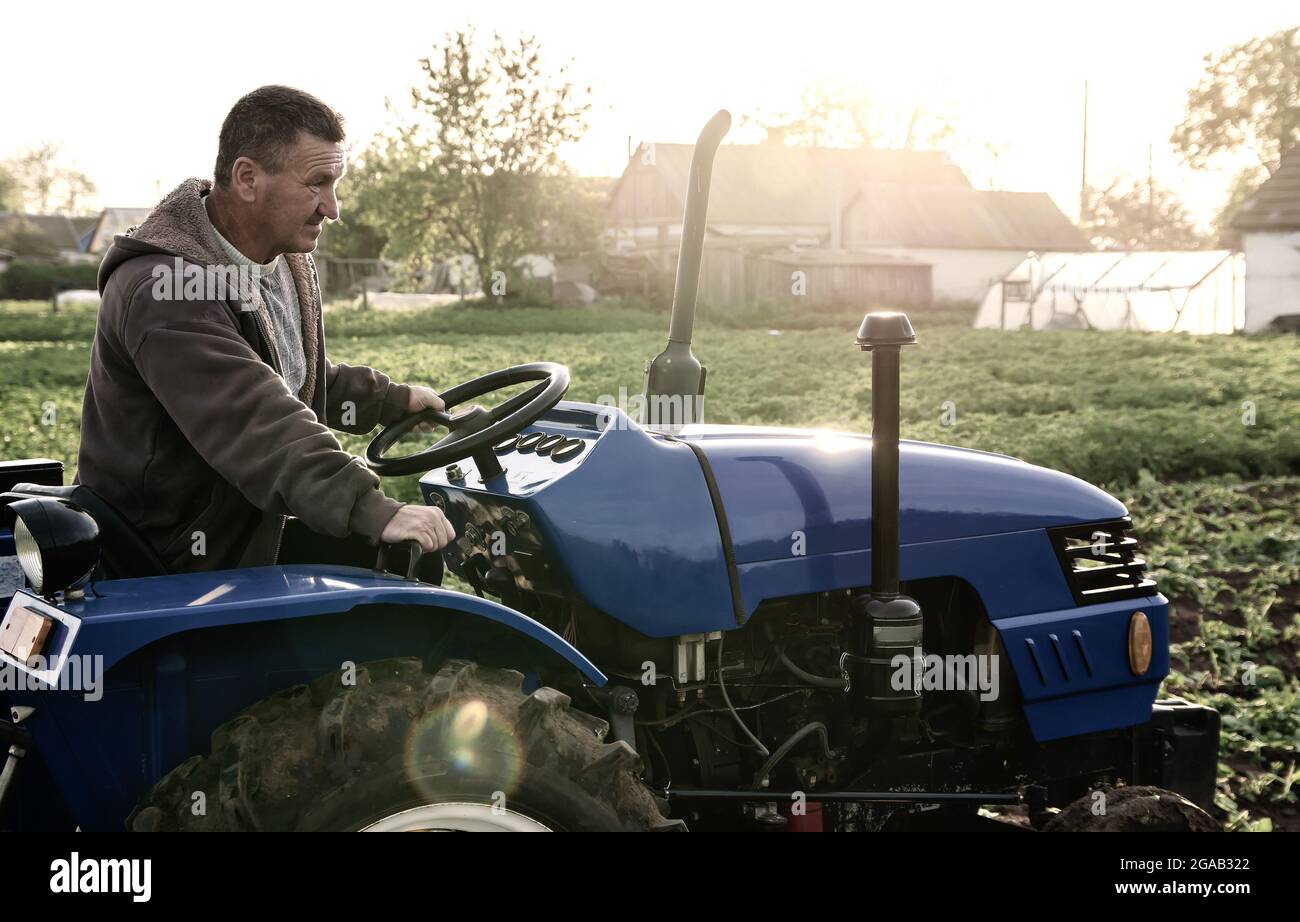 Farmer driving a tractor across the field. Agro industry, agribusiness ...