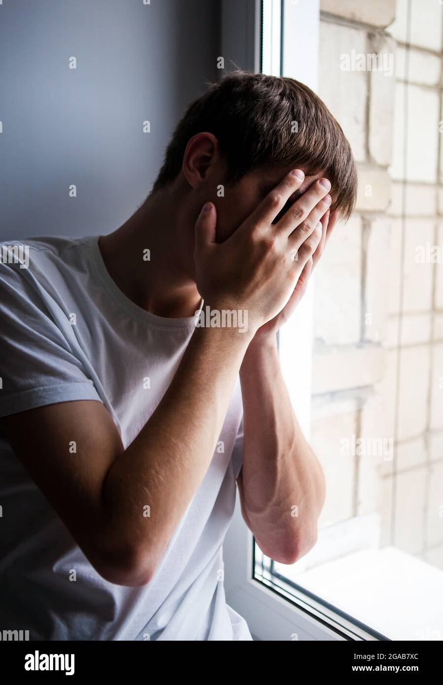 Sad Young Man by the Window in the Room Stock Photo - Alamy
