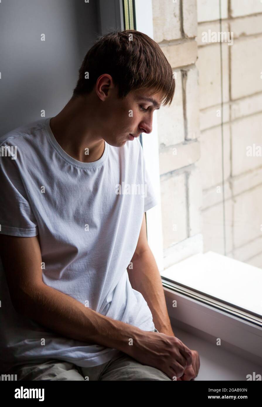 Sad Young Man by the Window in the Room Stock Photo - Alamy