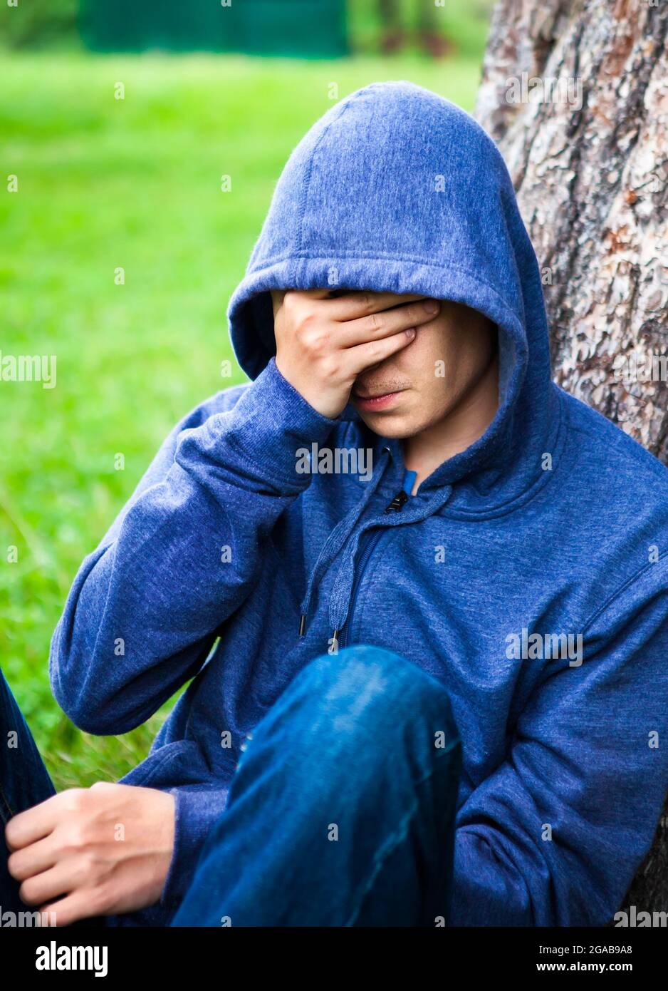 Sad Young Man sit under the Tree in the Park Stock Photo - Alamy