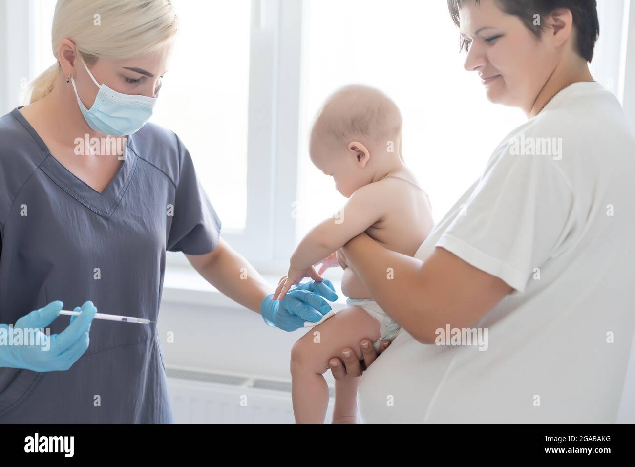 Pediatrician doctor with syringe, tense mother and baby Stock Photo - Alamy