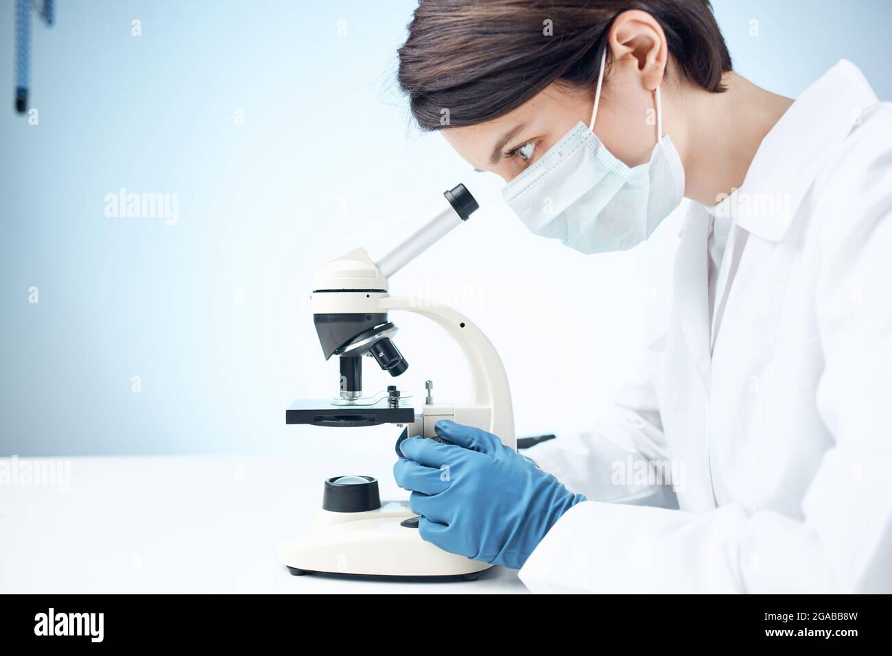 laboratory assistant looking through a microscope science research ...