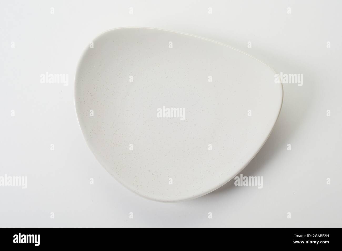 Top view of empty flat rounded triangle shaped white ceramic dessert ...