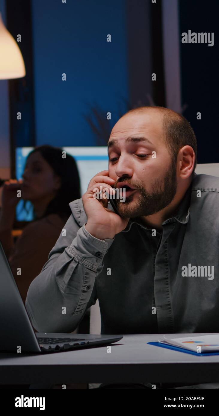 Stressed angry businessman sitting at desk table discussing corporate ...