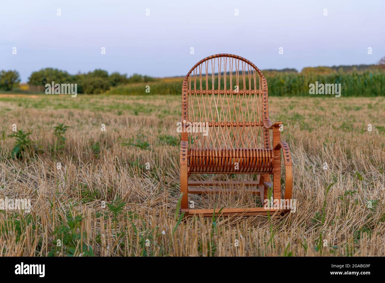 Empty rocking chair on a beveled field at sunset. Wicker rocking chair ...