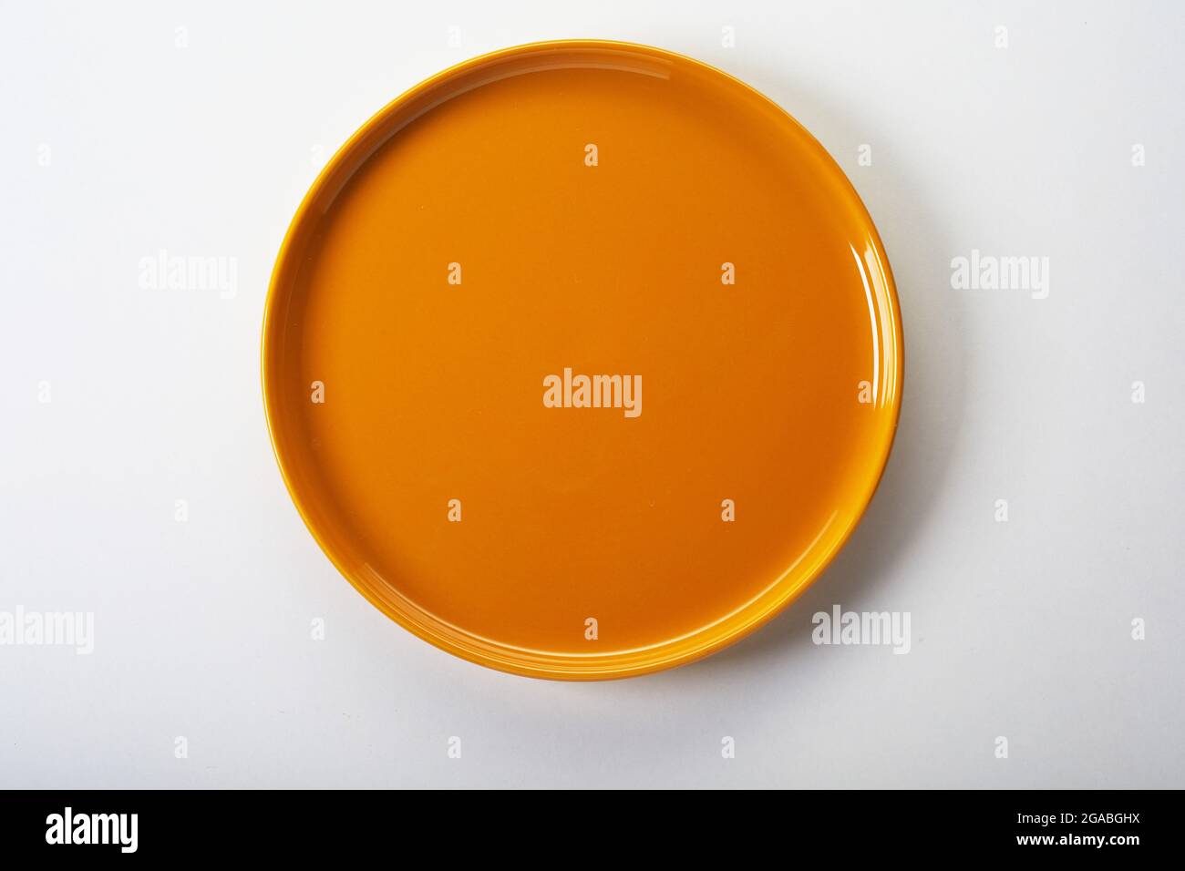 Top view of empty clean round bright orange ceramic platter on white ...