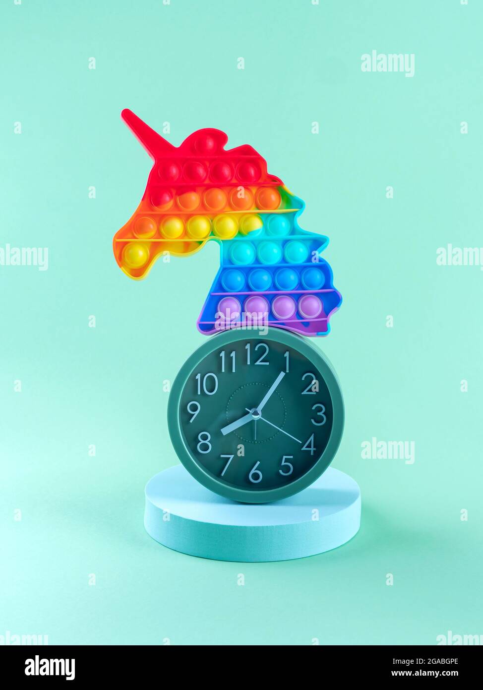 Geometric still life with rainbow unicorn pop it toy, alarm clock and ...