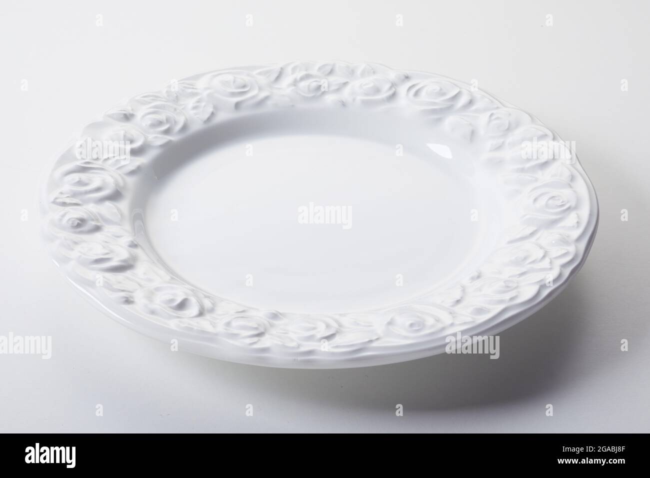 High angle of empty round flat white porcelain dinner plate with floral ...