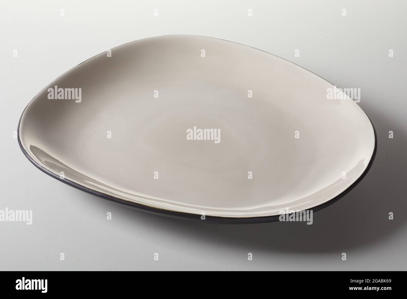 From above ceramic plate of unusual shape with shiny beige enamel ...