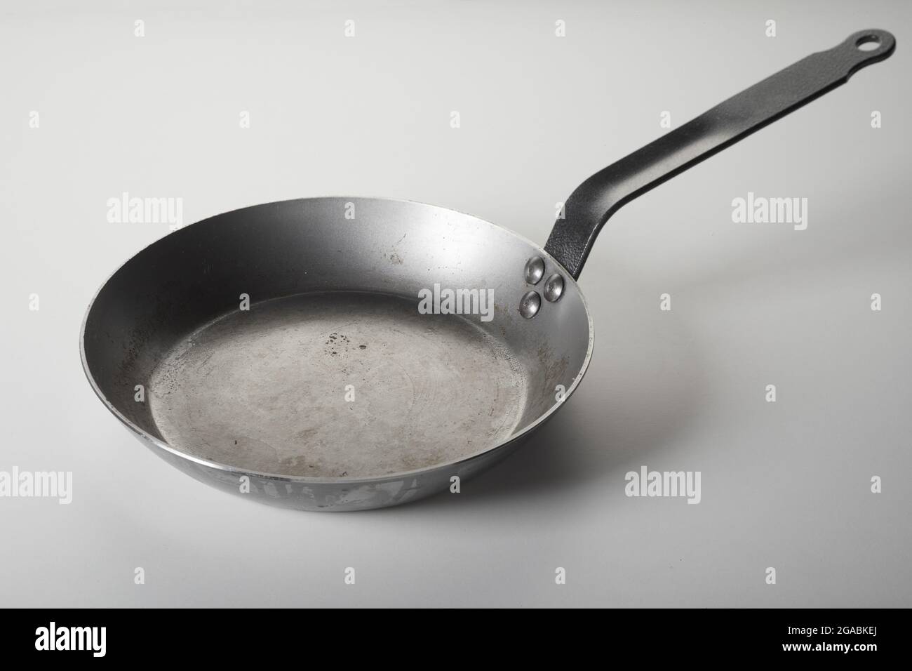High angle of empty metal frying pan with scratches placed on white ...