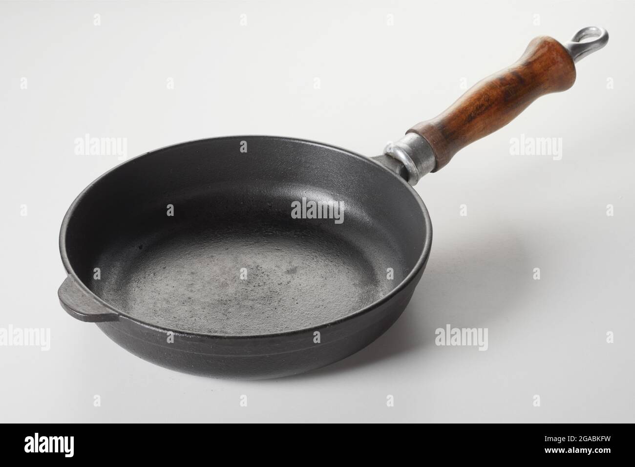 High angle of empty deep cast iron frying pan with wooden handle on ...